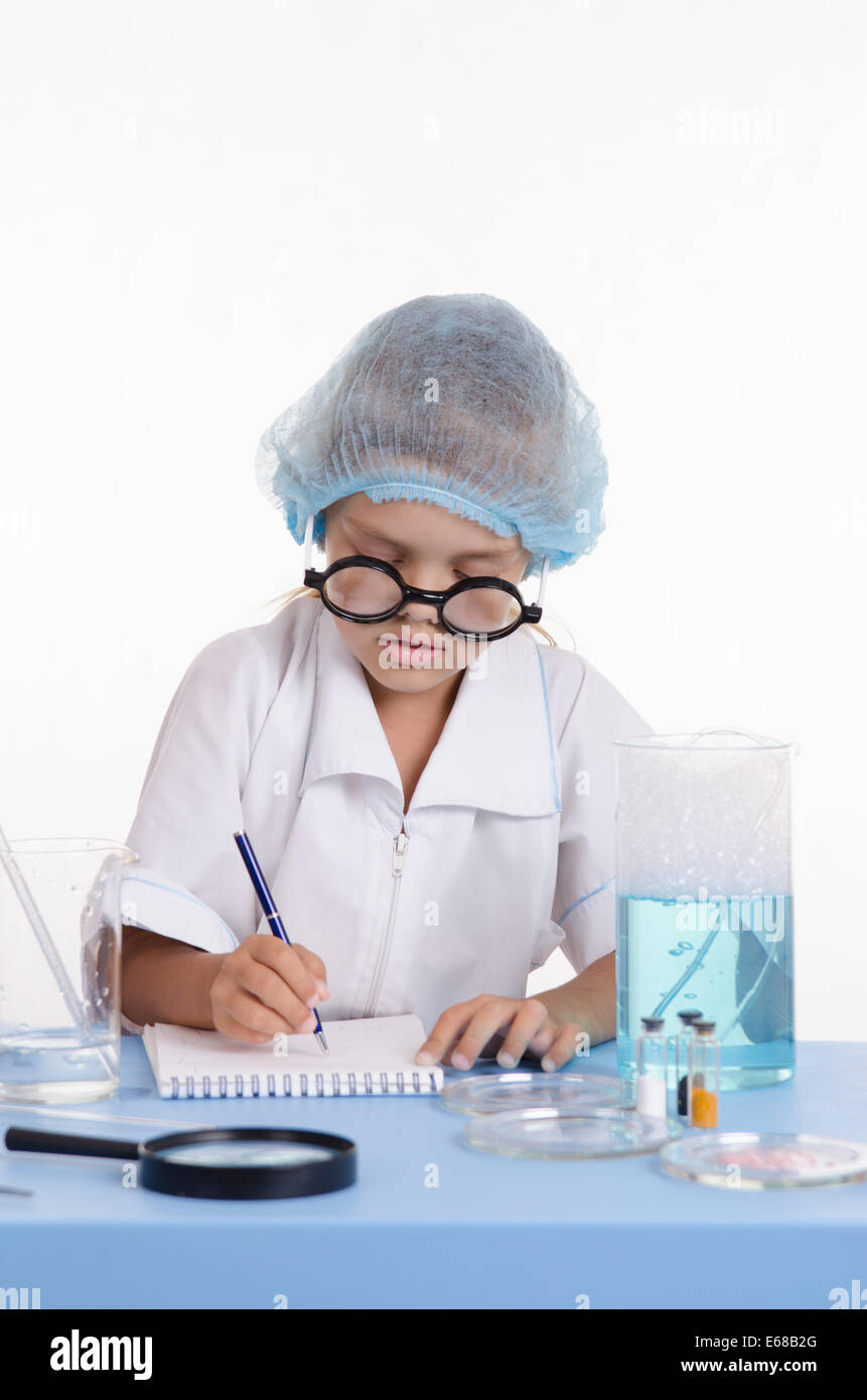 Chemist girl sitting at the table with the reagents in chemistry class ...
