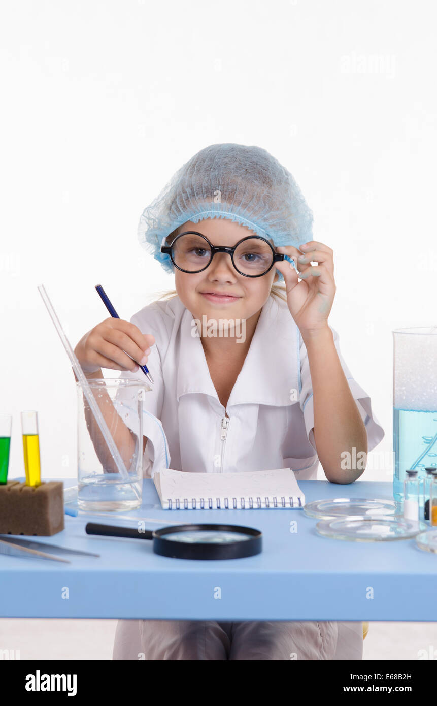 Chemist girl sitting at the table with the reagents in chemistry class ...