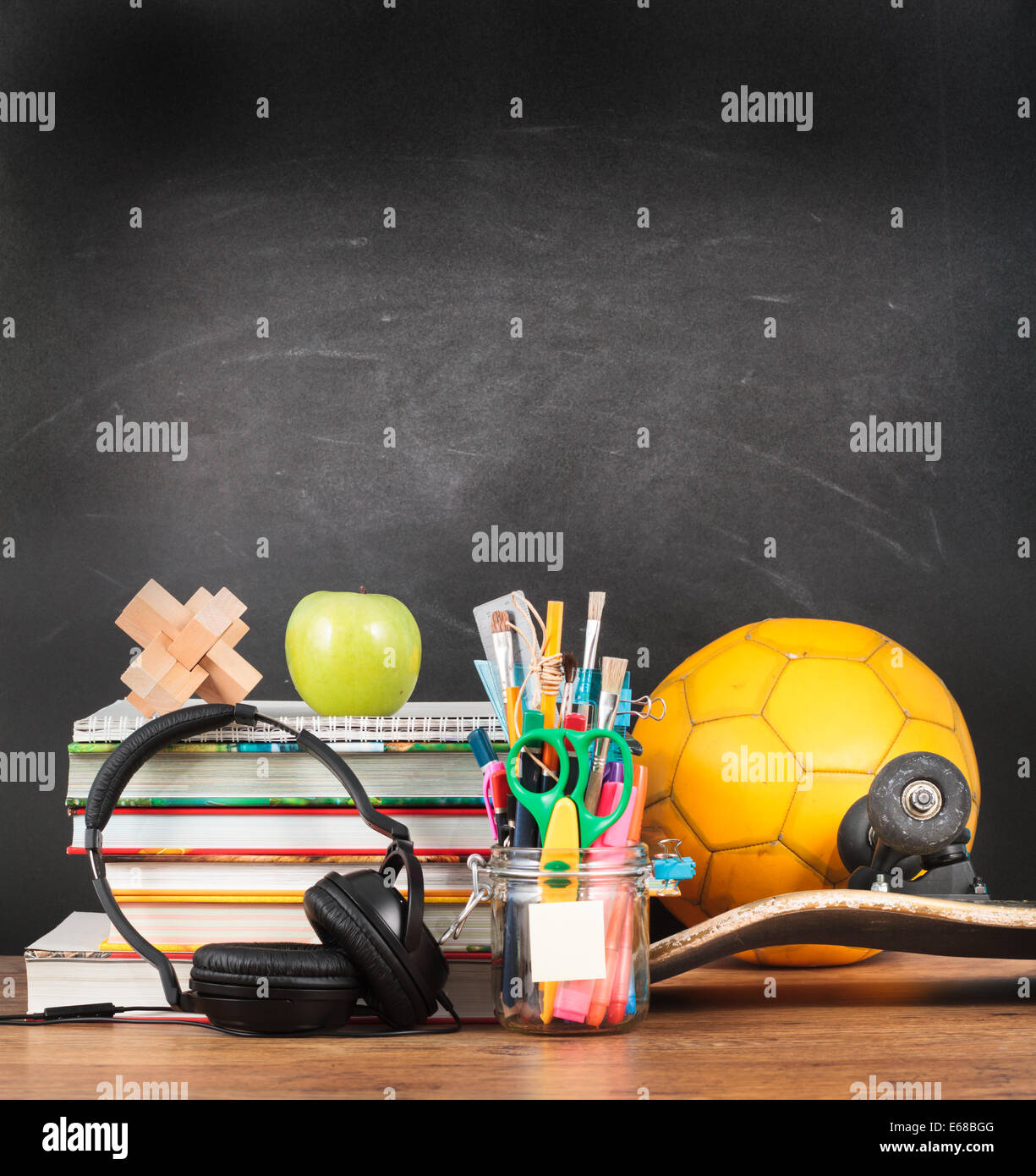 School accessories on desktop with blank blackboard in the background ...