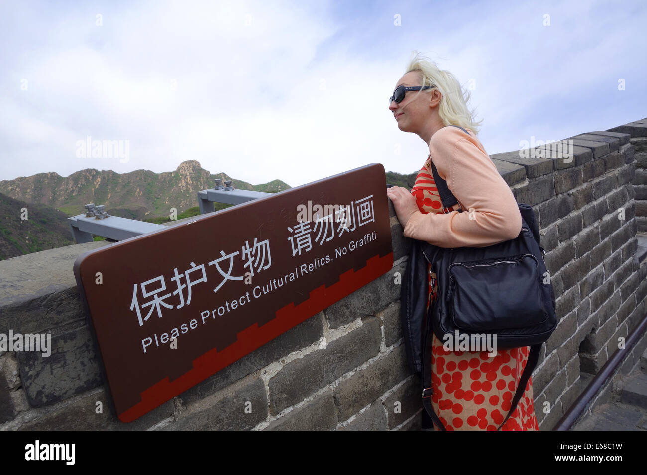 Great Wall of China, woman by a sign warning to protect cultural relics ...