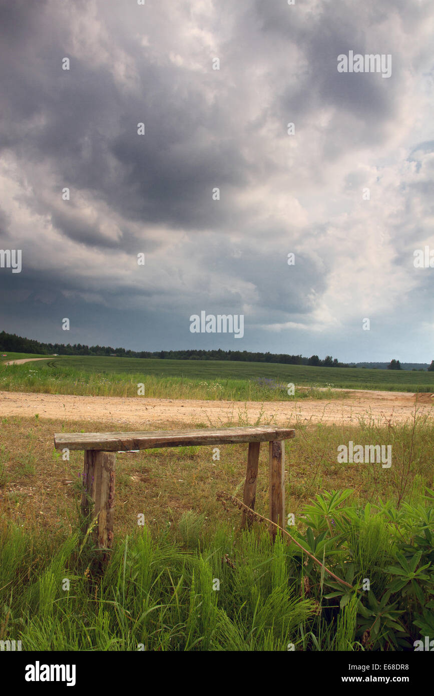 bench stands in a field near the road Stock Photo - Alamy
