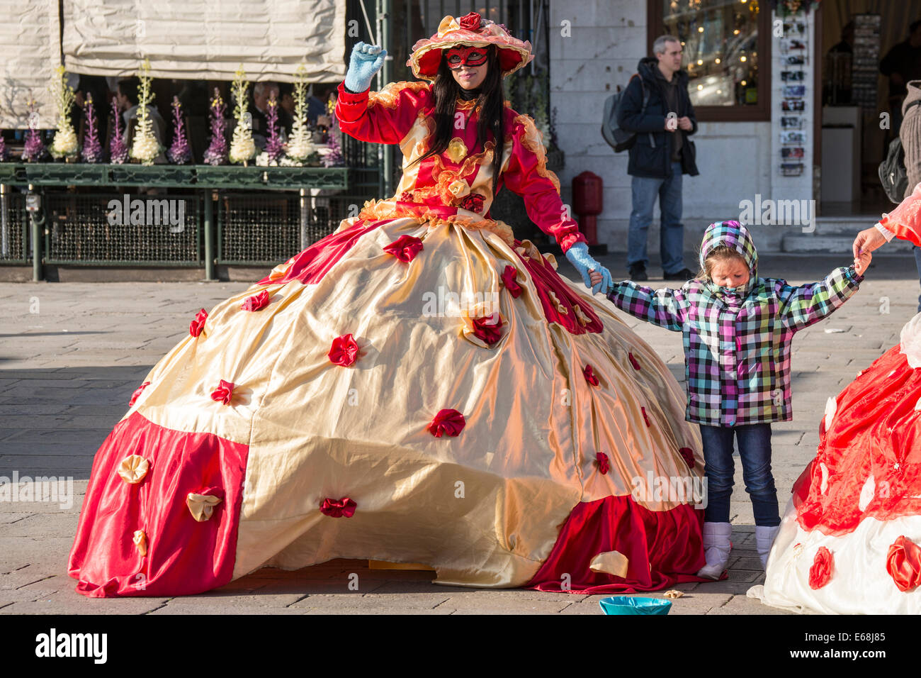 Street performer in Carnival costume poses with a little girl on the ...