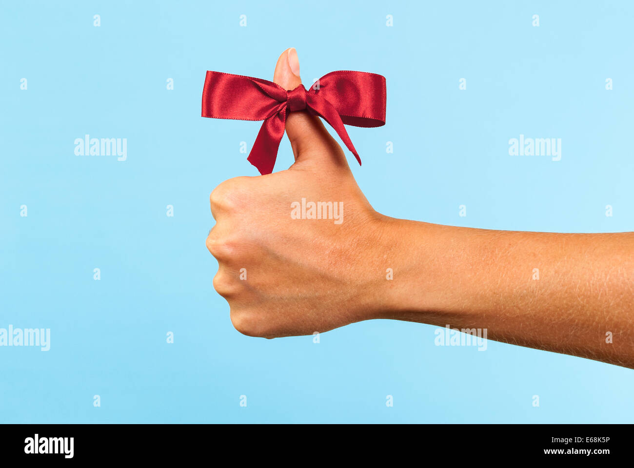 Hand with a red ribbon bow making thumb up gesture Stock Photo - Alamy