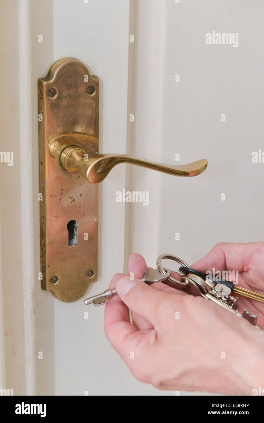 A man's hand holding bunch keys in the lock of a white door Stock Photo ...