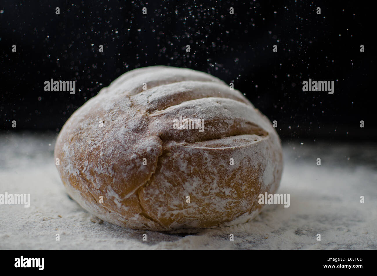 Homemade country bread with flour rain over dark background Stock Photo ...
