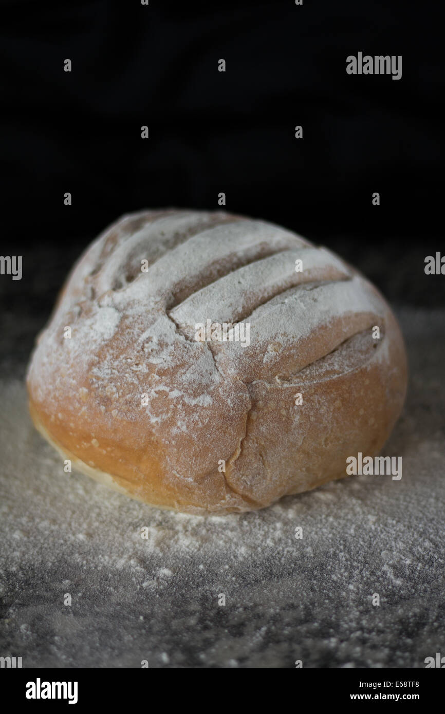 Homemade country bread with flour rain over dark background Stock Photo ...