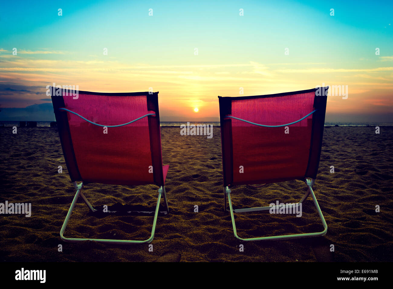 Two beach chairs on the beach facing a still horizon. Horizontal shot ...