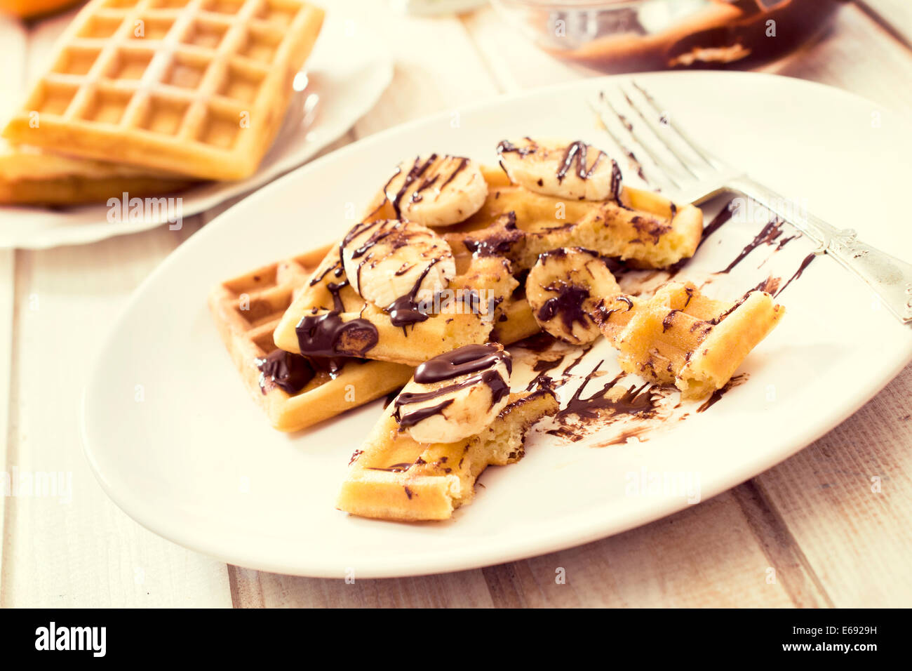 Selective focus on the front waffles in plate wit chocolate and bananas ...