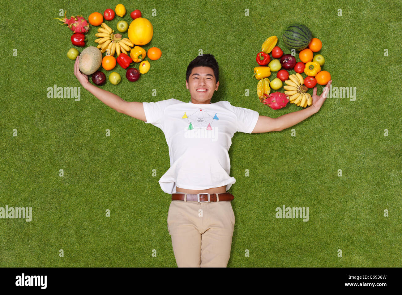 Young man lying on grass with fruits Stock Photo - Alamy