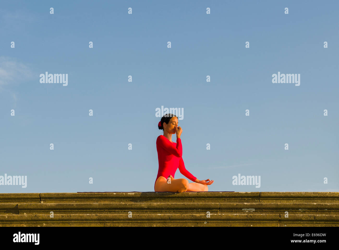 Young woman practising Hatha yoga, outdoors, showing the pose Anuloma ...