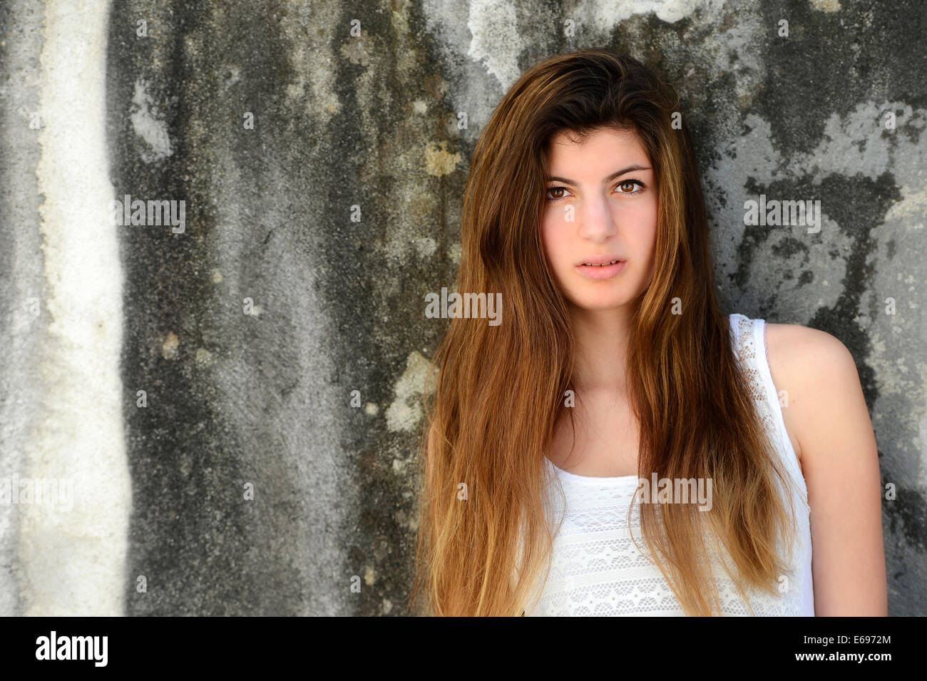 Girl with long hair, 15 years, standing in front of an old weathered ...