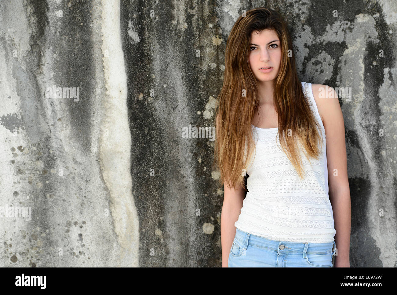 Girl with long hair, 15 years, standing in front of an old weathered ...