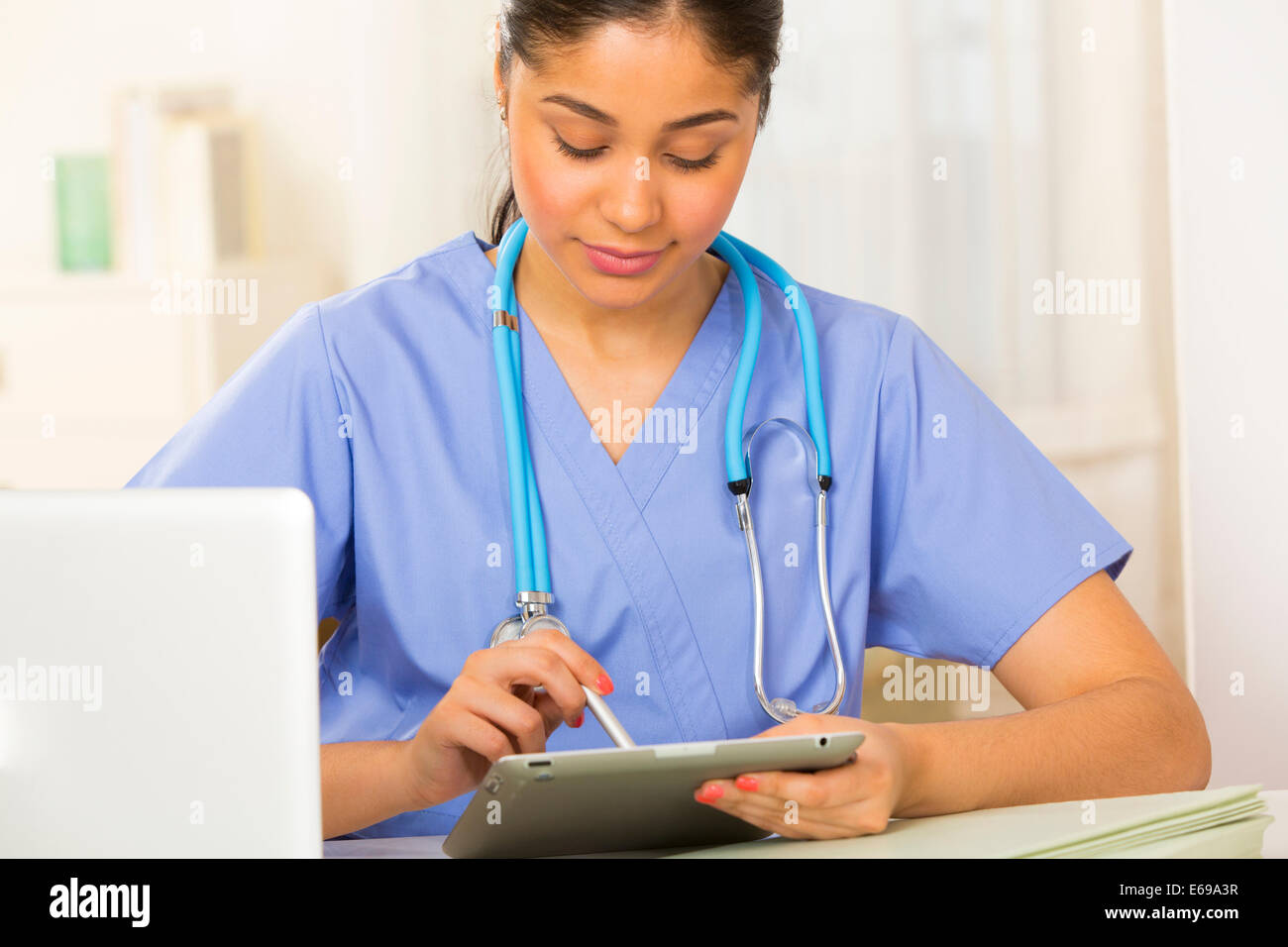 Hispanic nurse using tablet computer at desk Stock Photo - Alamy