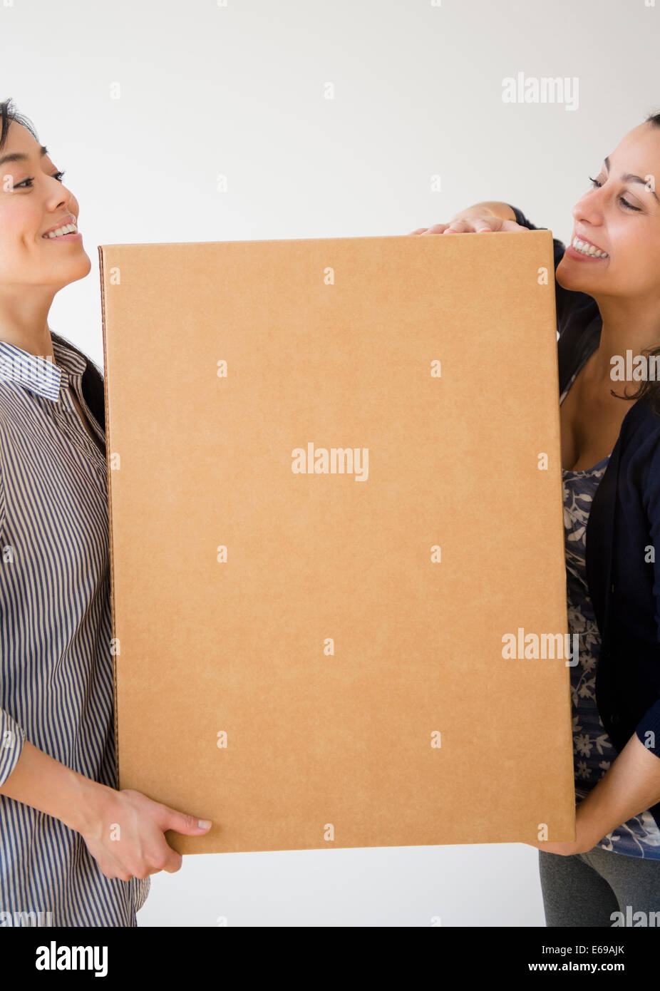 Women carrying cardboard box together Stock Photo - Alamy