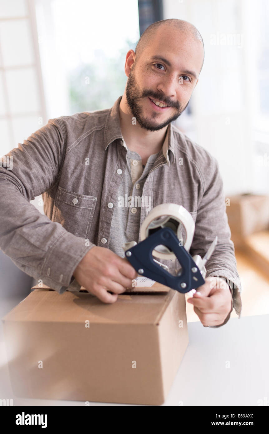 Hispanic man taping cardboard box Stock Photo - Alamy