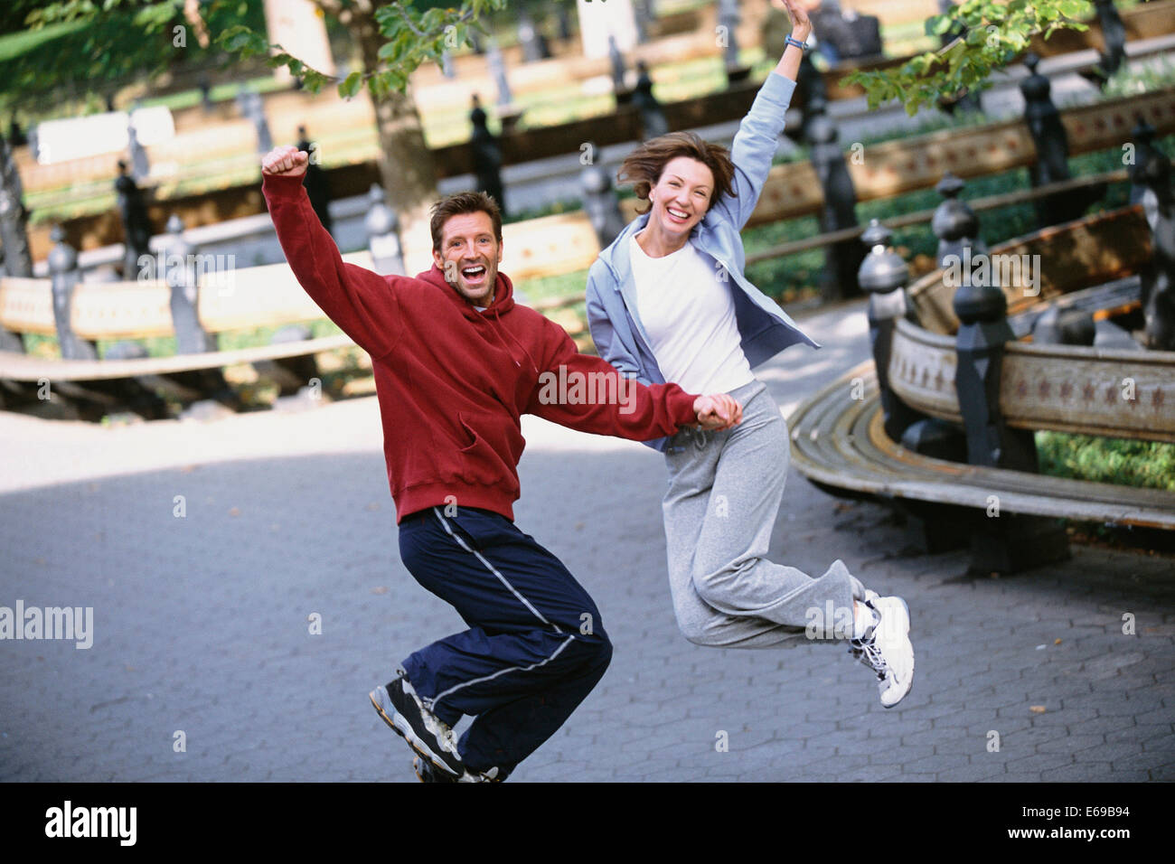 Couple jumping for joy in urban park Stock Photo - Alamy