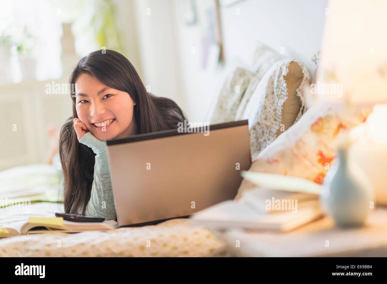 Mixed race teenage girl doing homework on bed Stock Photo - Alamy