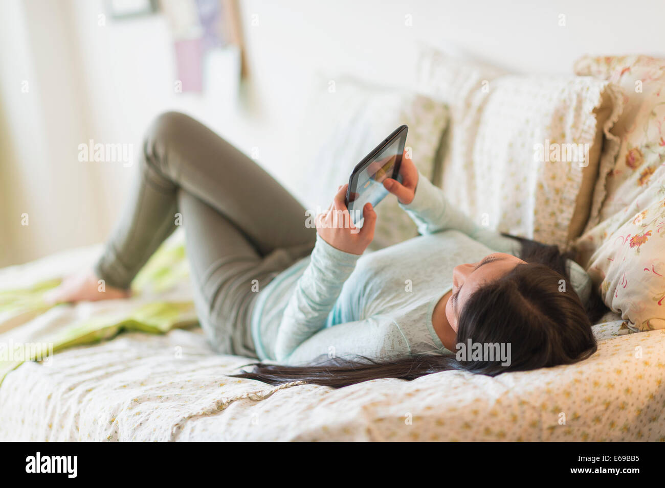 Mixed race teenage girl using digital tablet on bed Stock Photo - Alamy