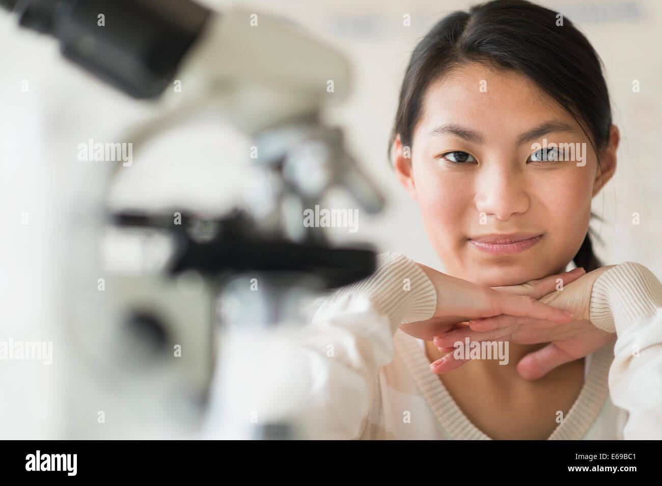Mixed race teenage girl smiling in science lab Stock Photo - Alamy