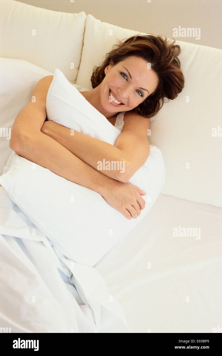 Woman hugging pillow in bed Stock Photo - Alamy