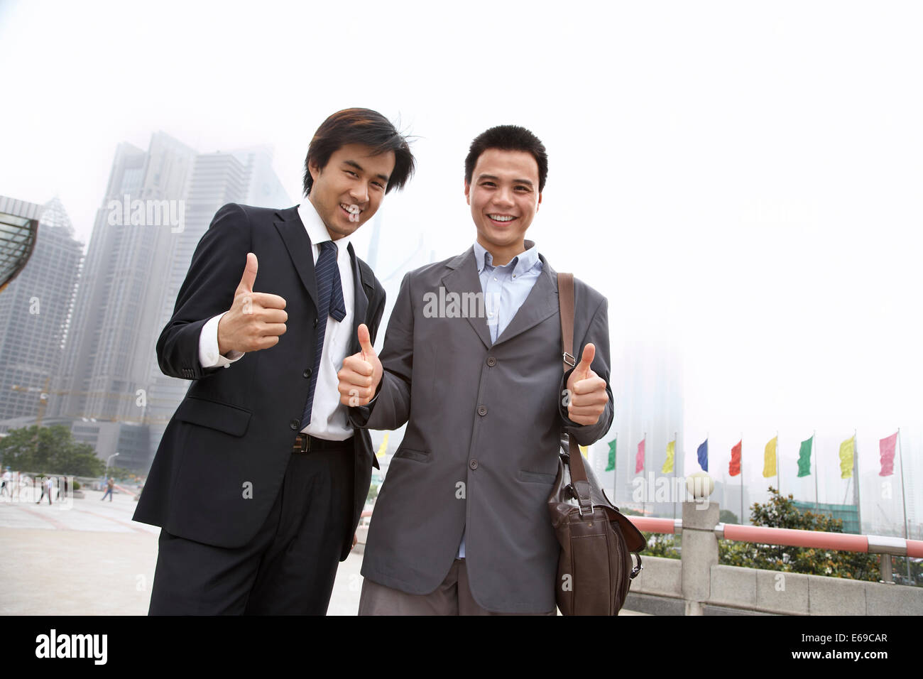 Chinese businessmen giving 'thumbs up' on city street, Shanghai, China ...