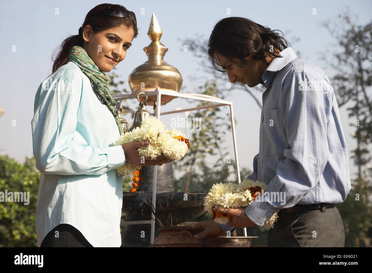 Indian couple offering flowers to shrine Stock Photo - Alamy
