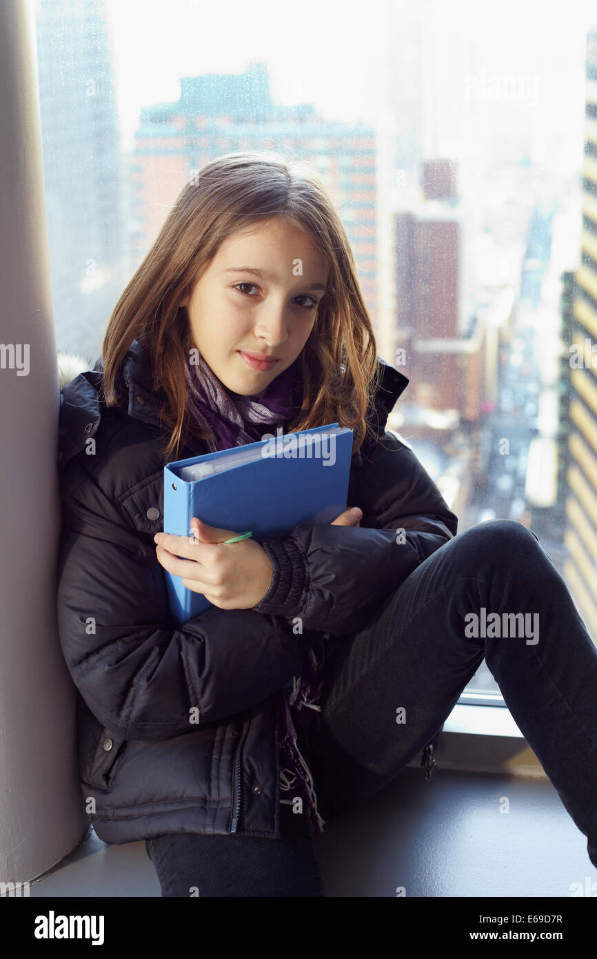 Girl holding binder on windowsill Stock Photo - Alamy
