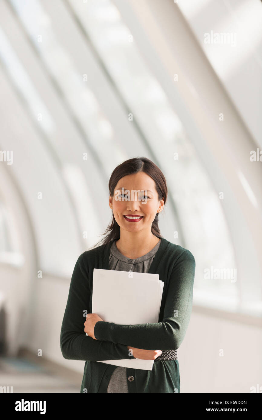 Japanese businesswoman carrying papers in lobby Stock Photo - Alamy