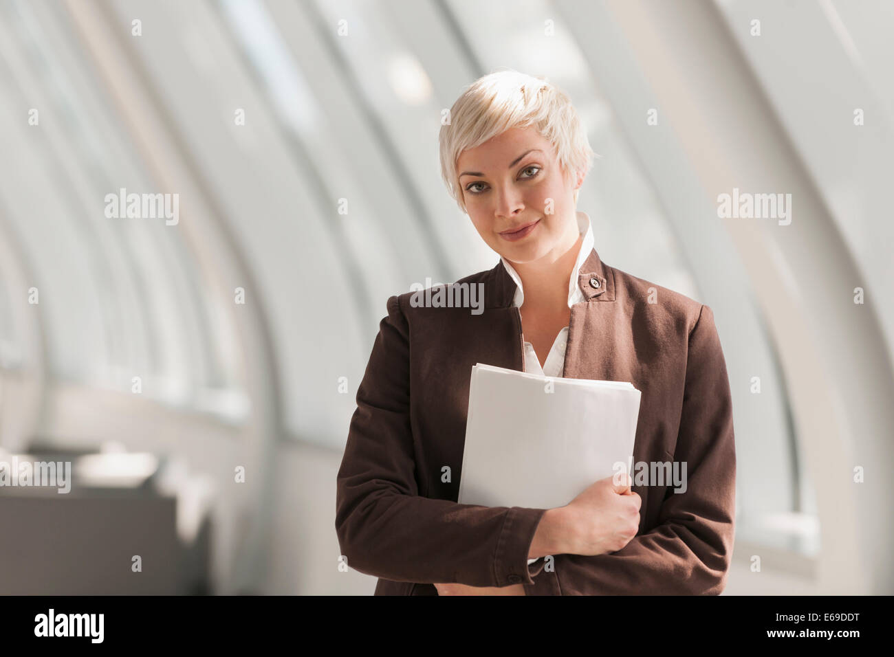 Caucasian businesswoman carrying papers in lobby Stock Photo - Alamy