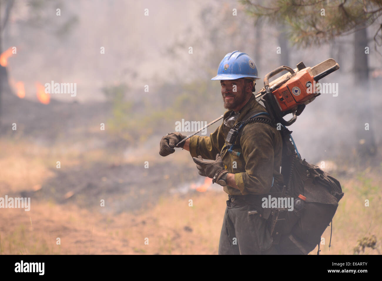 A firefighter takes a break before moving along the fire line near ...