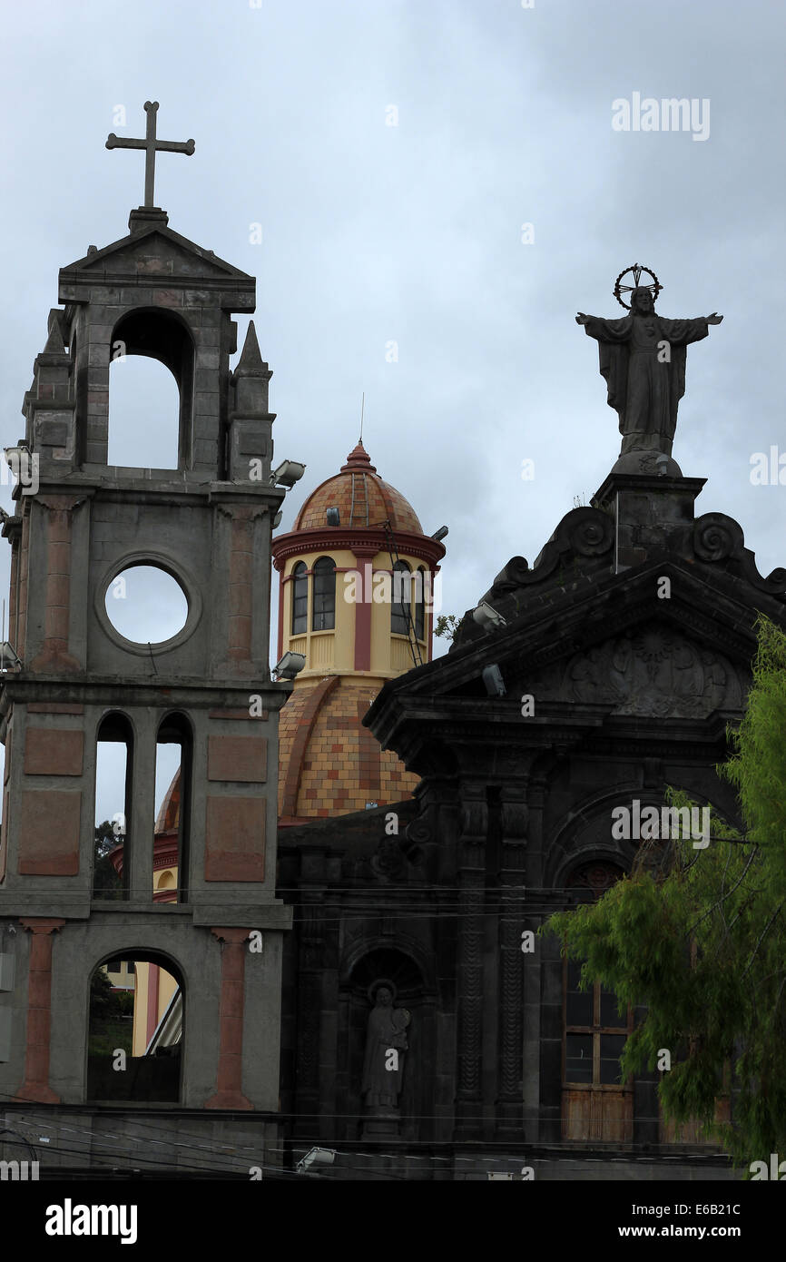 A statue, cross and tower on an old Catholic Church in Otavalo, Ecuador ...