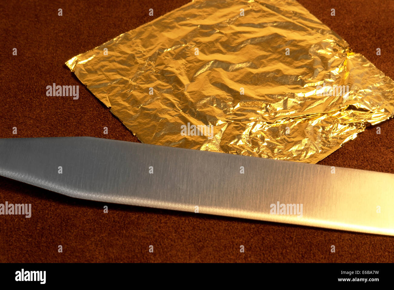 gilding theme with a leaf of beaten gold and blade on brown leather ...