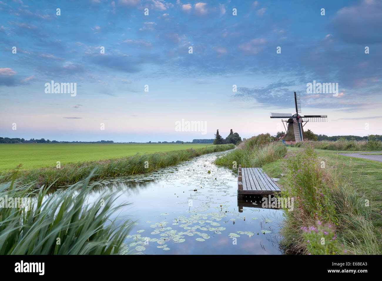 Dutch windmill by river at sunset, Holland Stock Photo - Alamy