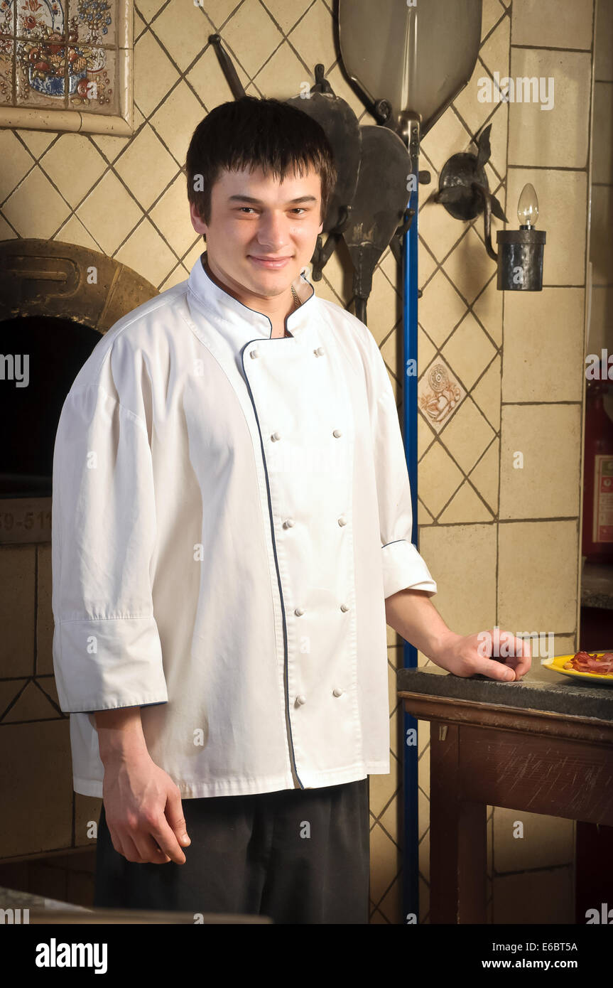 Young chef standing next to oven - indoor Stock Photo - Alamy