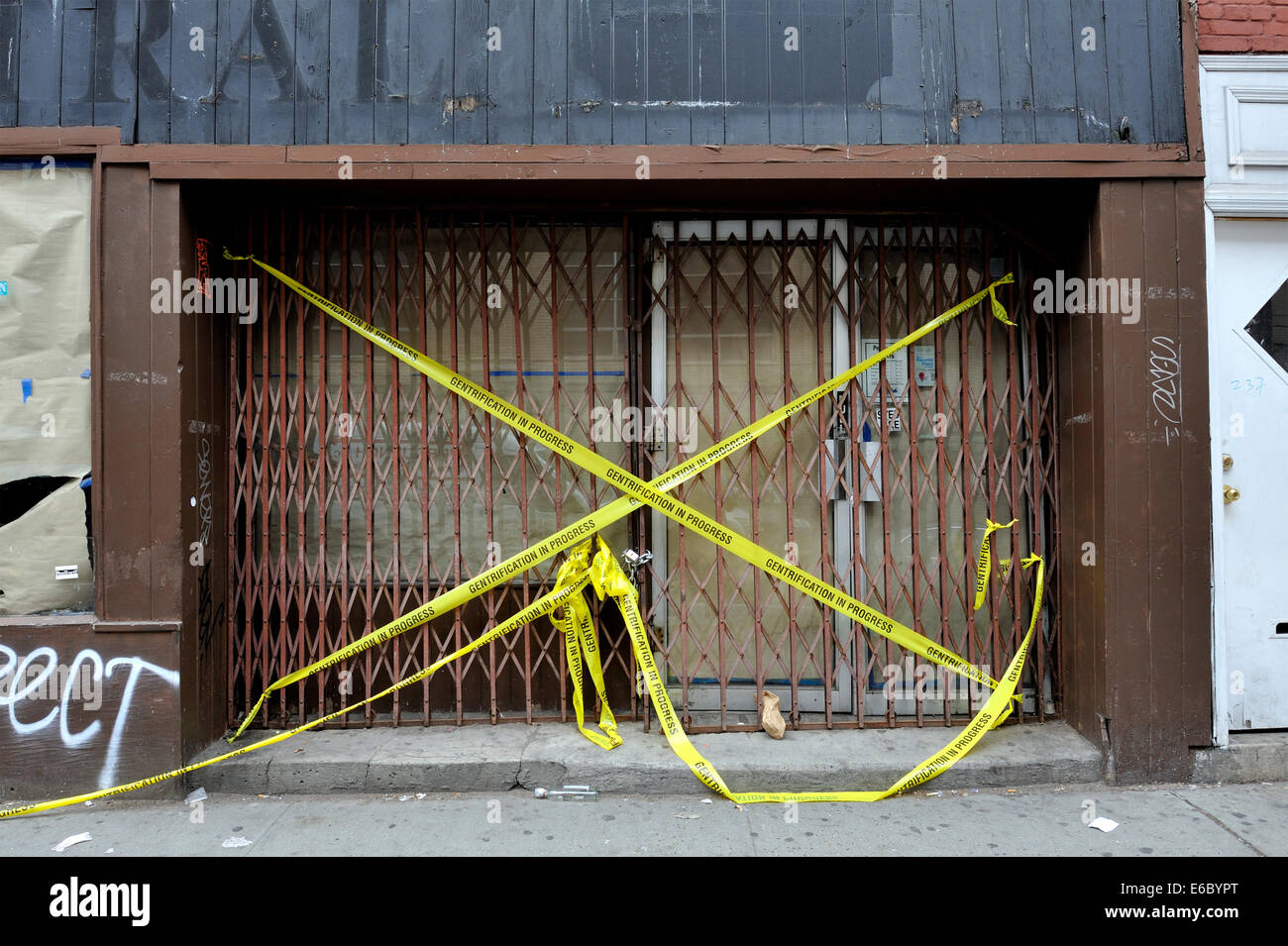 Boarded up entrance to building, with tape indicating "Gentrification ...
