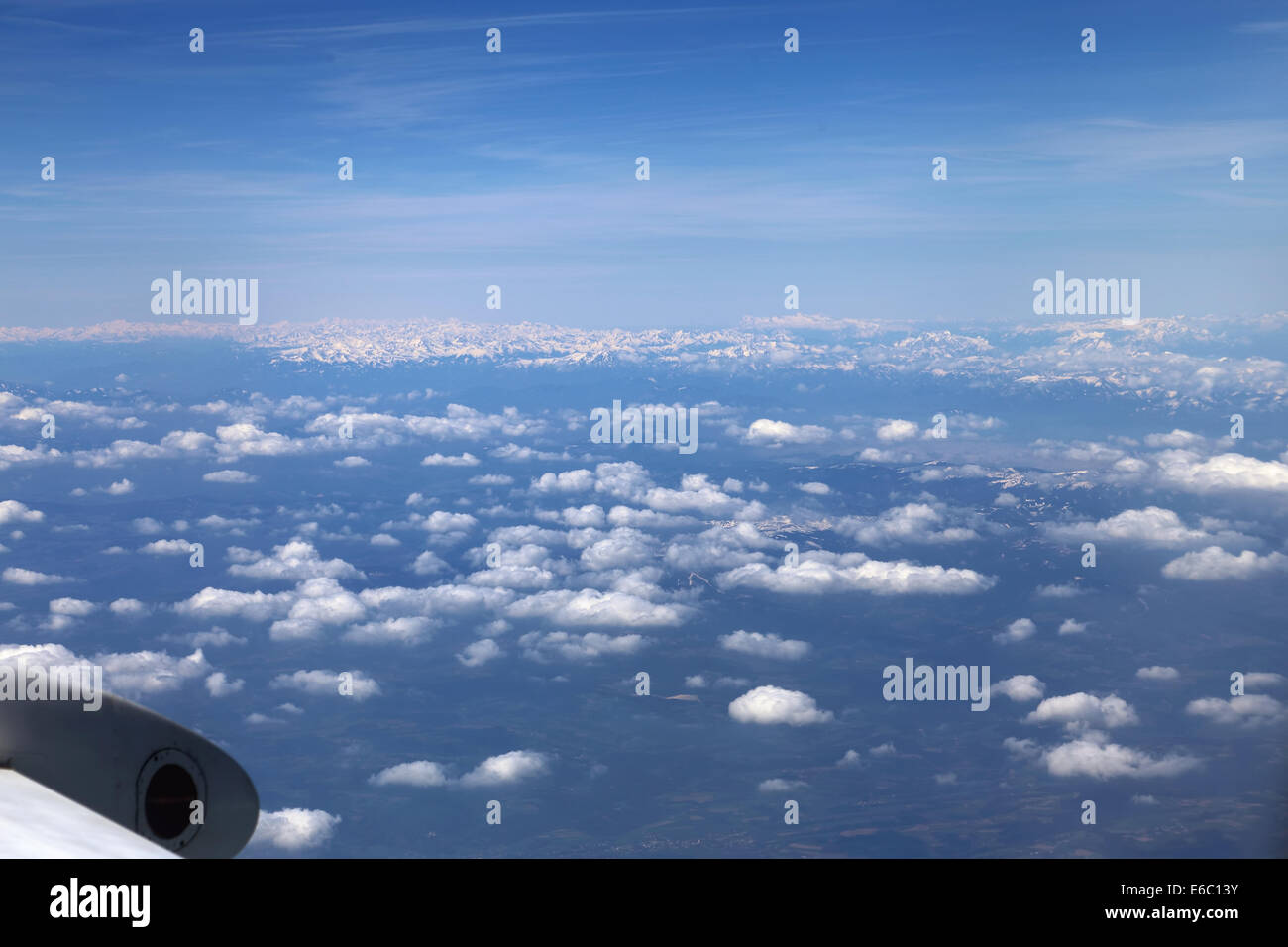 Wing of the plane on blue sky background and snowy mountains below ...