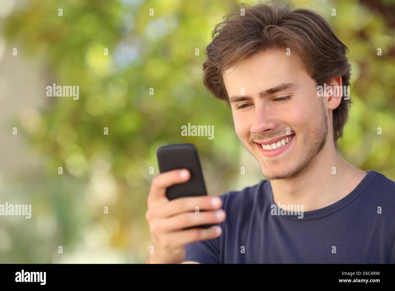 Happy man using a smart phone outdoor with a green background Stock ...
