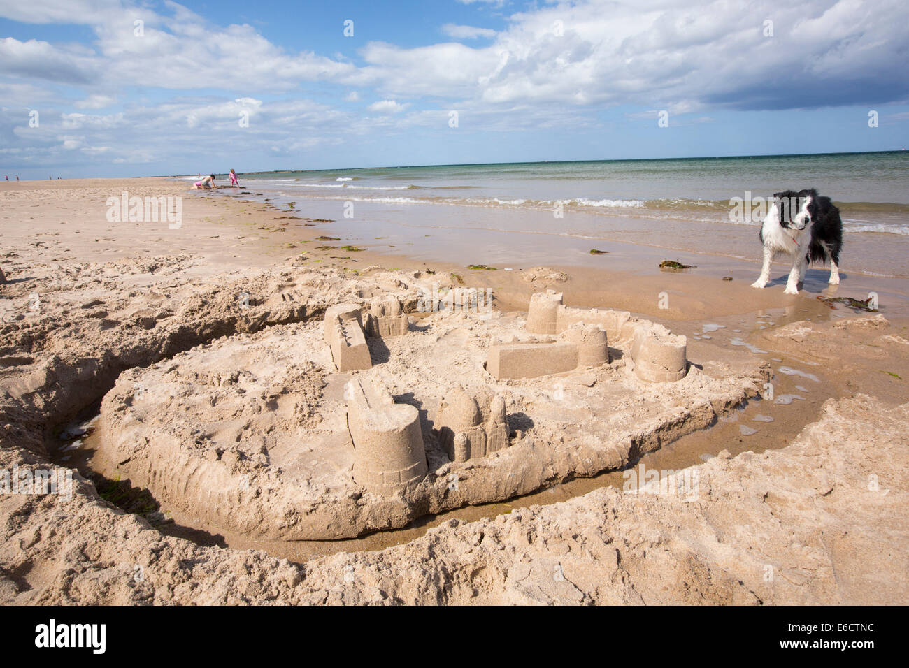 A sandcastle on a beach in Northumberland, UK, with the incoming tide ...