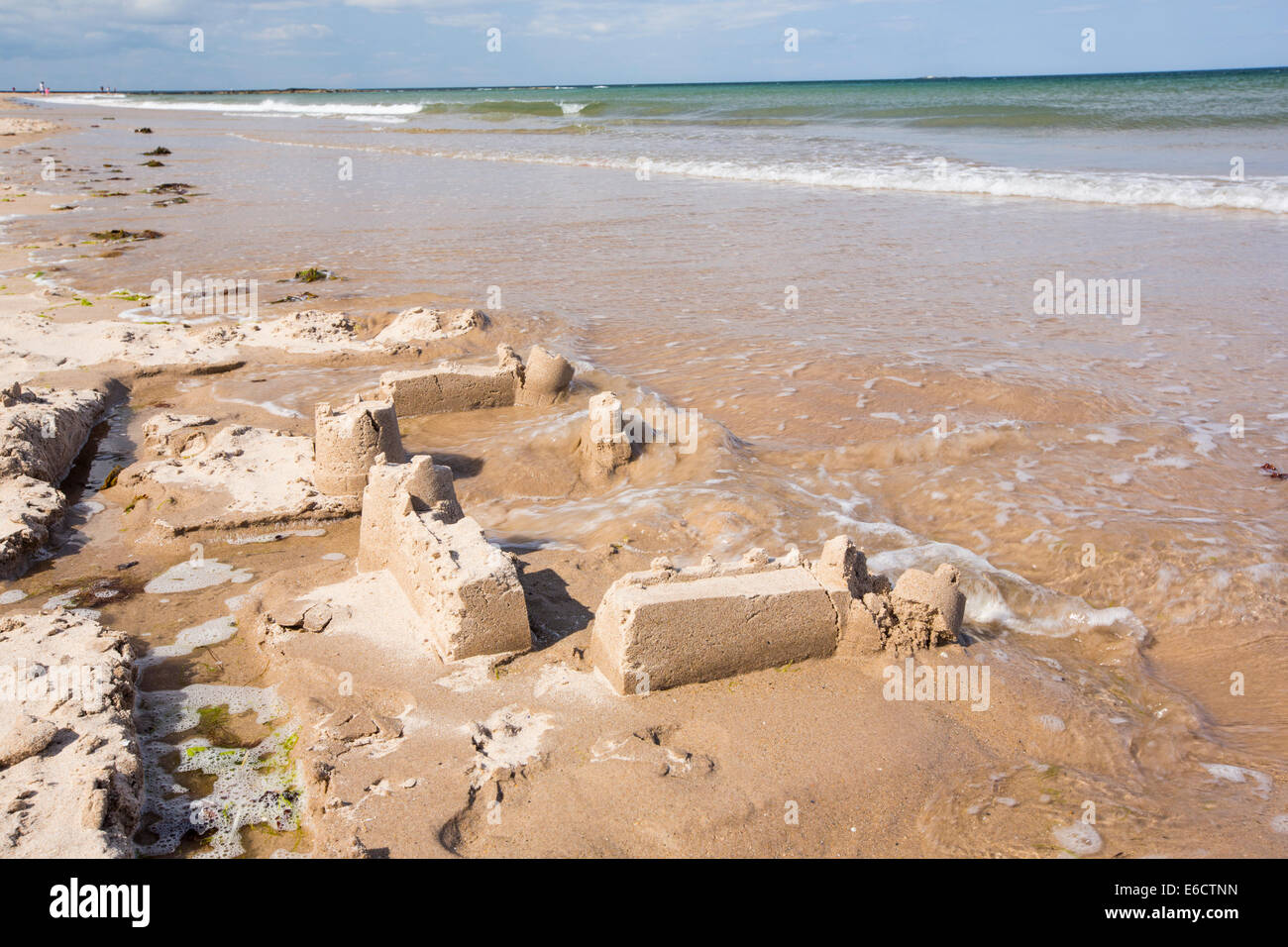 A sandcastle on a beach in Northumberland, UK, being washed away by the ...