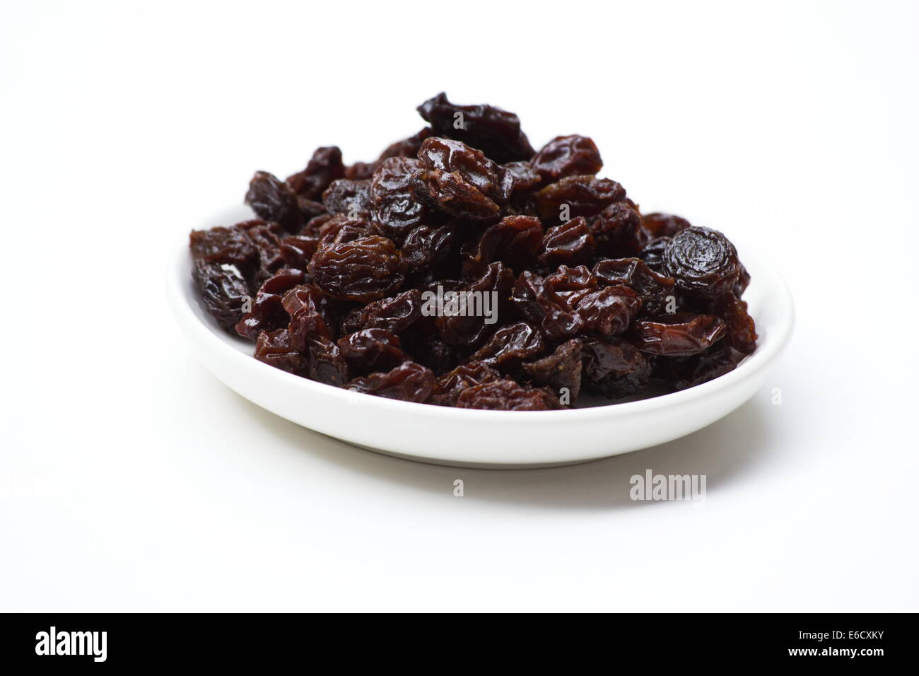 Raisins in a white dish on white background Stock Photo - Alamy