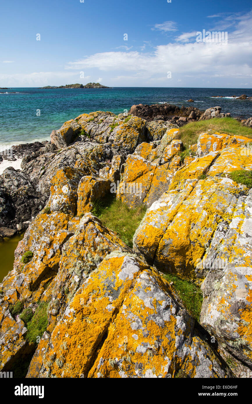 Aquamarine seas and lichen covered rock on the West coast of Iona, off ...