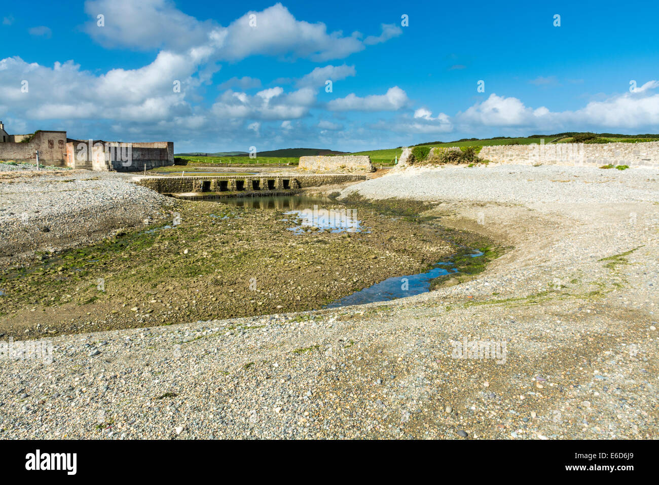 Bridge structure and other buildings viewed from beach at Cemlyn Bay ...