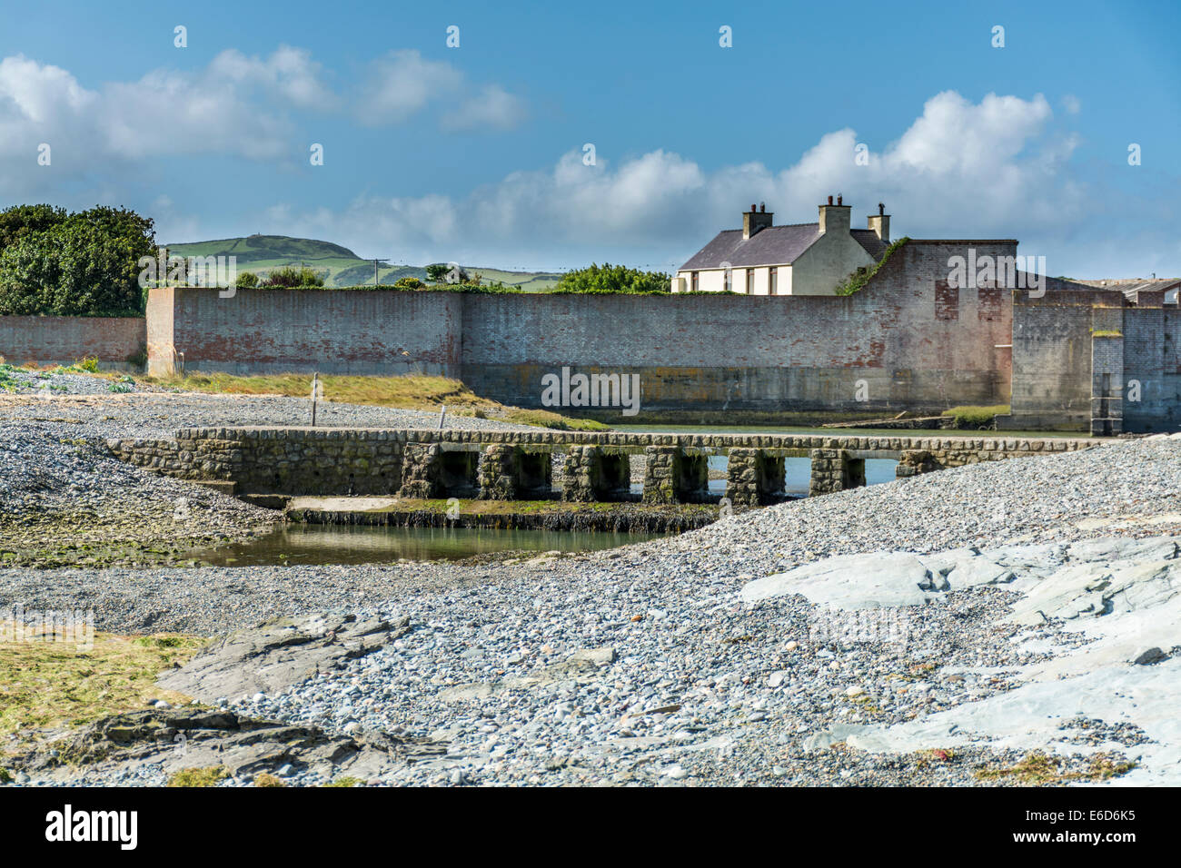 Bridge structure and other buildings viewed from beach at Cemlyn Bay ...