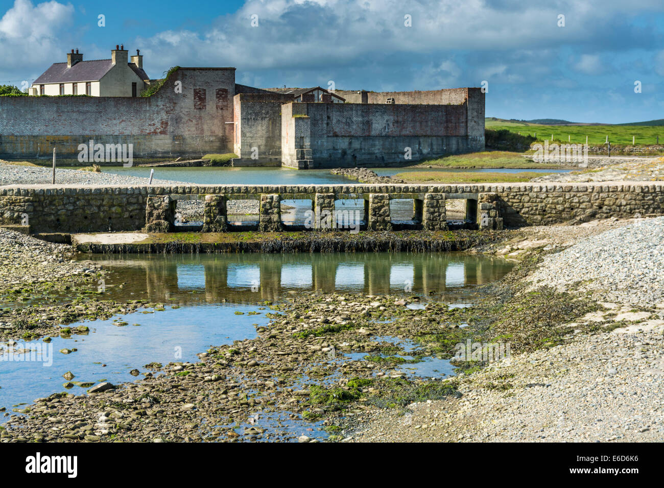 Bridge structure and other buildings viewed from beach at Cemlyn Bay ...