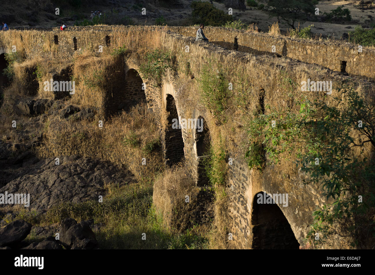 Young boy sitting on the ancient stone bridge, at the Blue Nile Falls ...