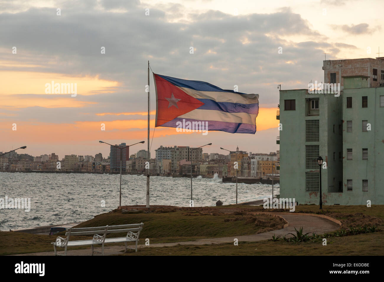 Cuban national flag flying in strong winds as waves break over the ...