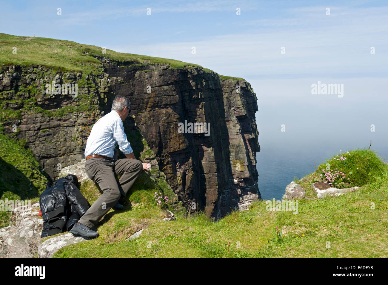 A walker looking over the cliffs at Puffin Bay, Handa Island ...