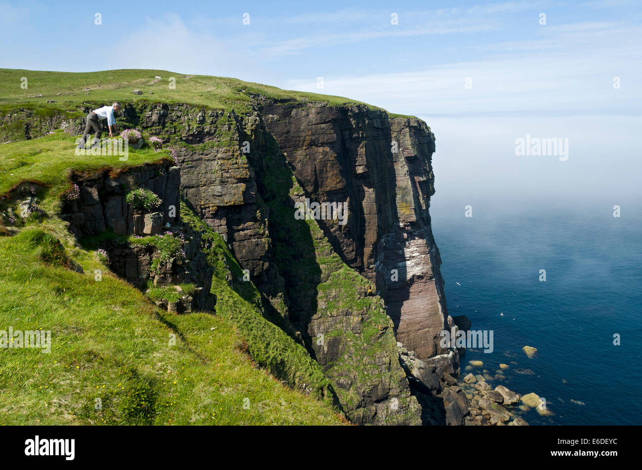 A walker looking over the cliffs at Puffin Bay, Handa Island ...