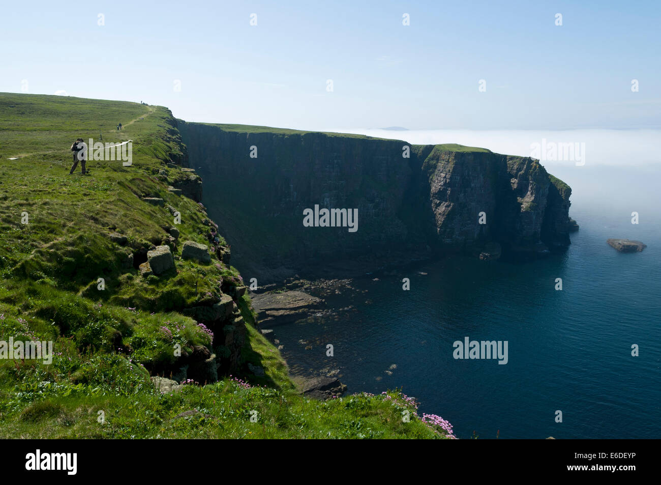 A walker on the cliff path on the western coast of Handa Island ...