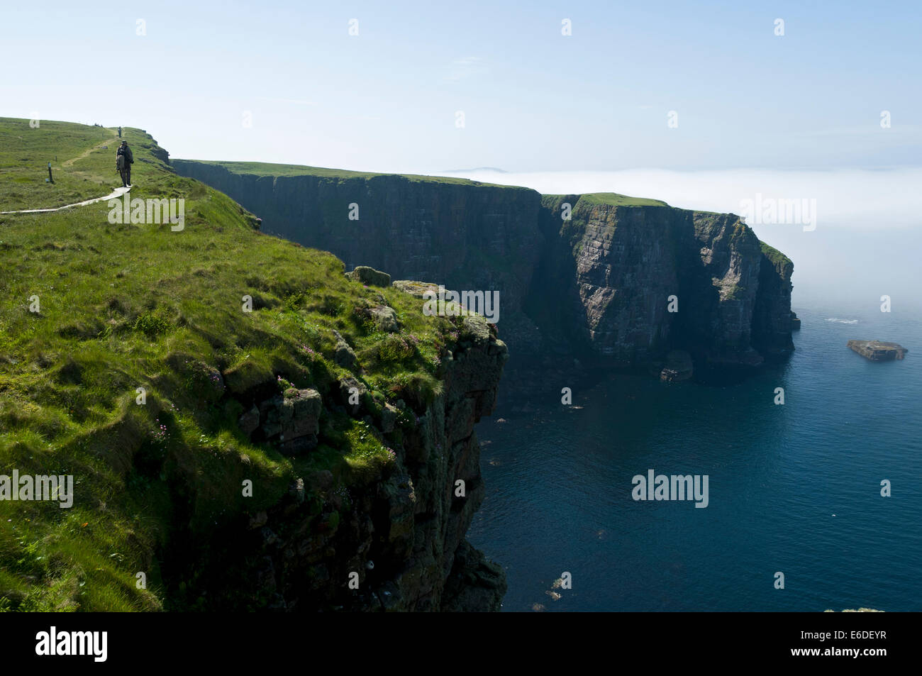 A walker on the cliff path on the western coast of Handa Island ...